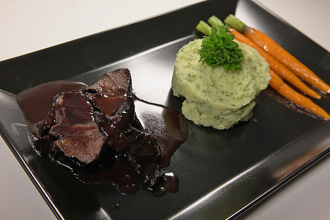 Geschmorte Ochsenbacken in Portwein mit glasierten Karotten und grünem ...